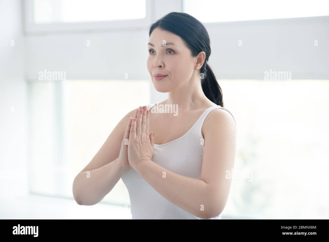Brunette female performing namaste, pressing hands together Stock Photo ...