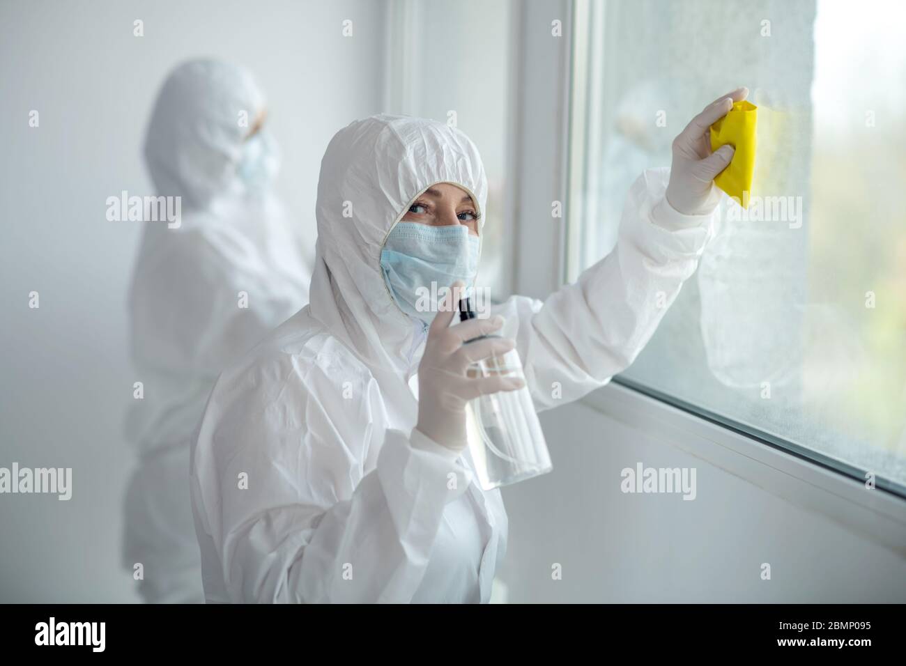 Medical workers in protective clothing and medical masks cleaning and ...