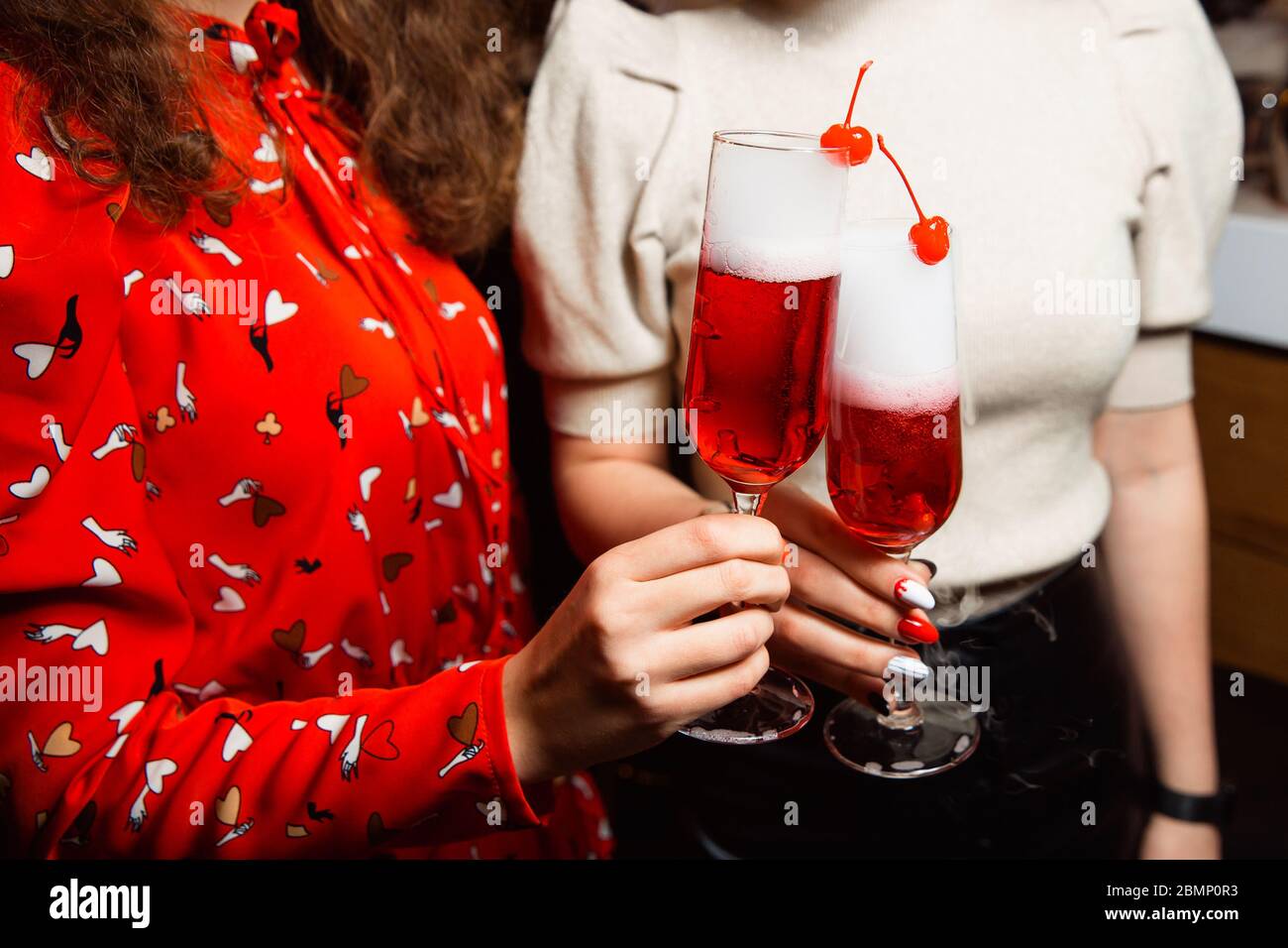 Holiday concept, hands of young girls holding glasses with drinks ...