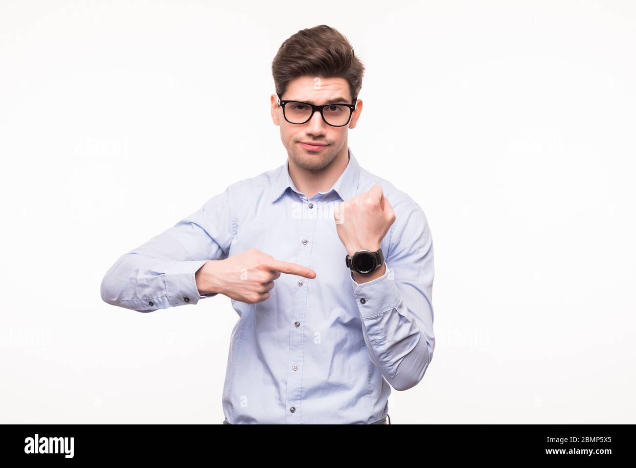 Handsome young man pointing at his smart watch on white background ...