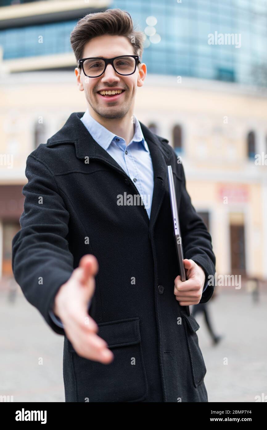Smiling young man offering handshake. Front view of cheerful traveler ...