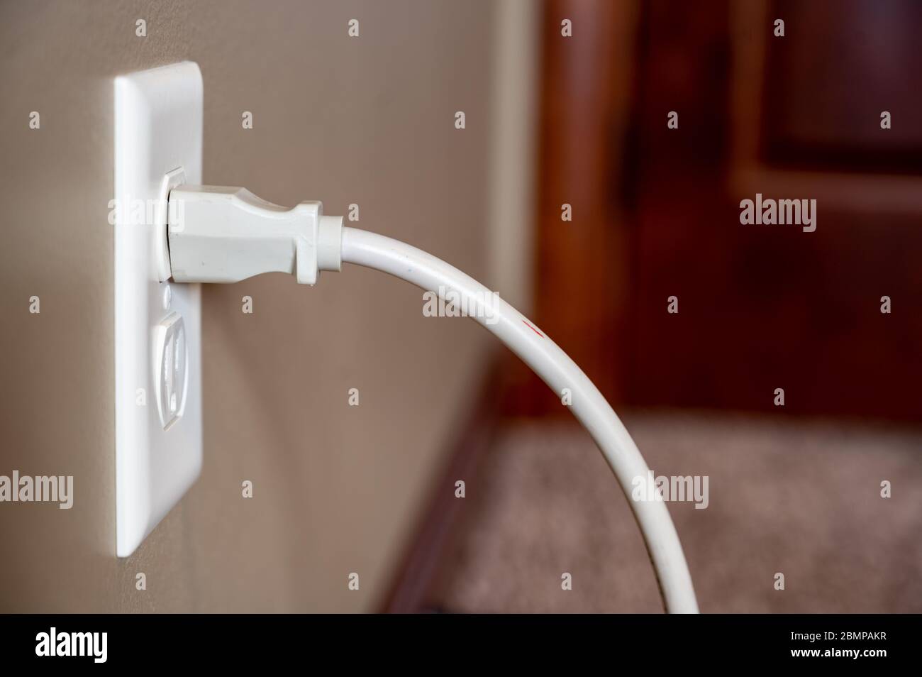 Side view of white power cord plugged into a white wall outlet Stock ...