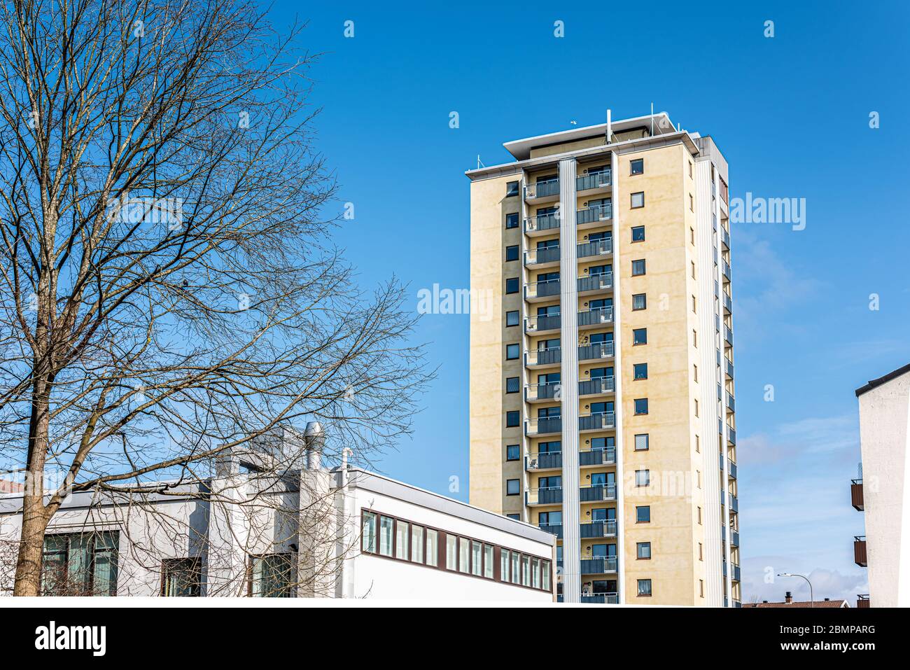 Beige high rise apartment building towering over lower buildings Stock ...