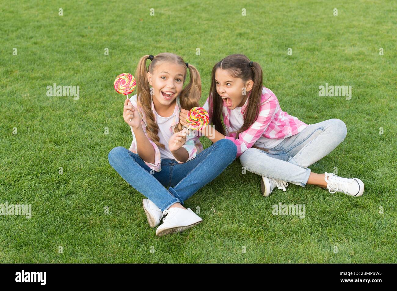 Happy children hold candy sit grass. Sugar and calories. Joyful ...