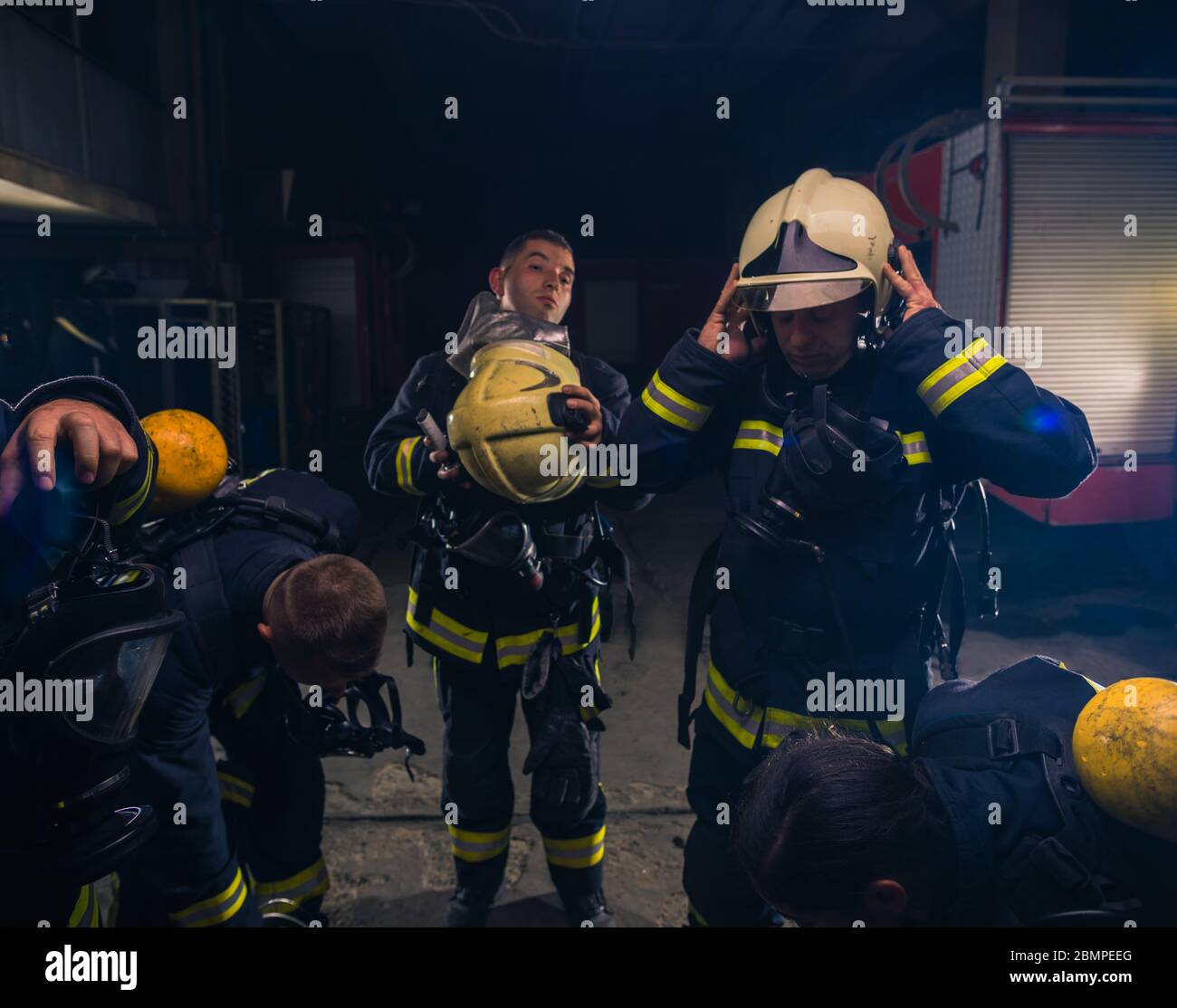 Group of firefighters standing inside the fire brigade wearing helmet ...