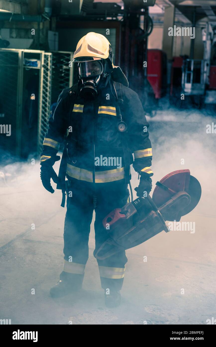 Portrait of a firefighter wearing full protective equipment posing with ...