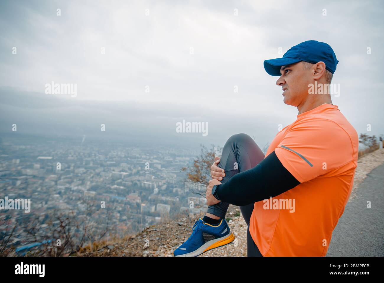 Older well built man in activewear stretching out his legs before ...