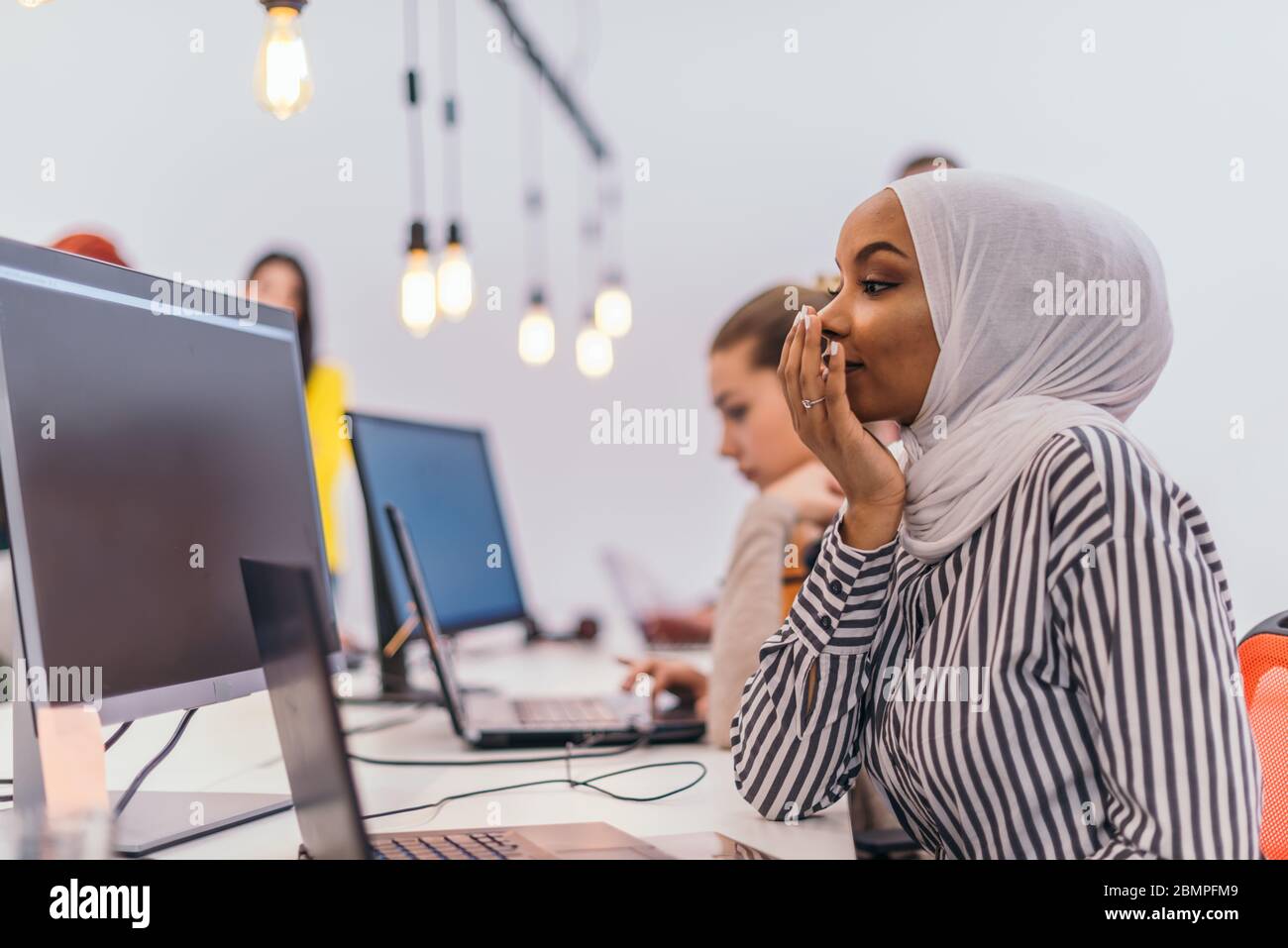Surprised african muslim woman working in bright coworking space on ...