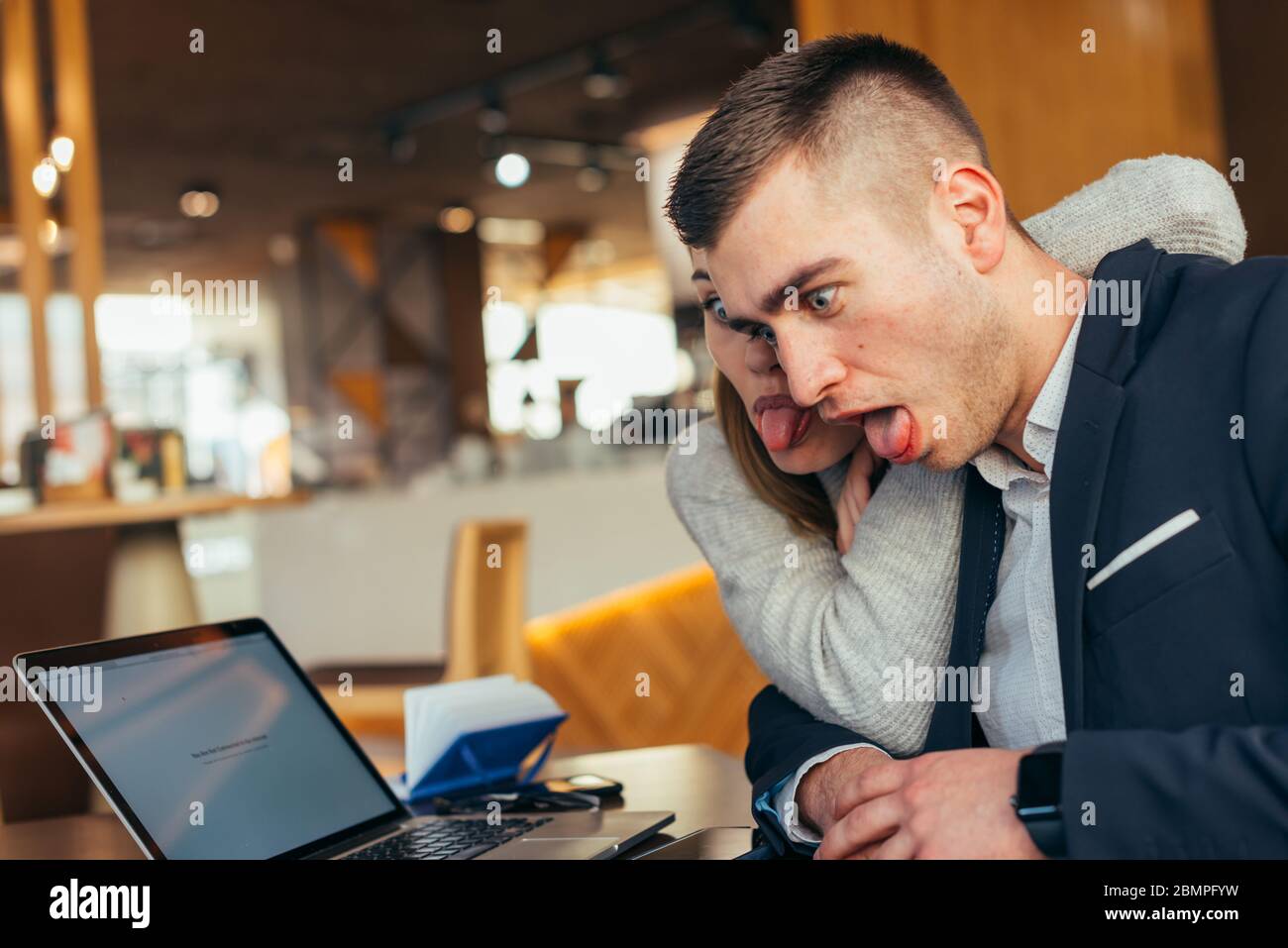 Couple having fun in a cafe ( coffee shop) while making crazy faces and ...