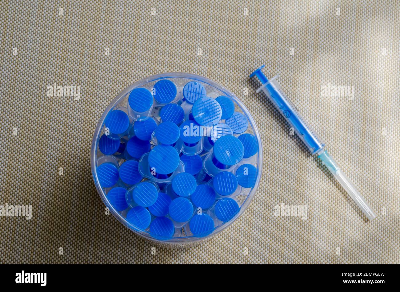 Many used syringes in a plastic jar. Blue medical syringes in a round ...