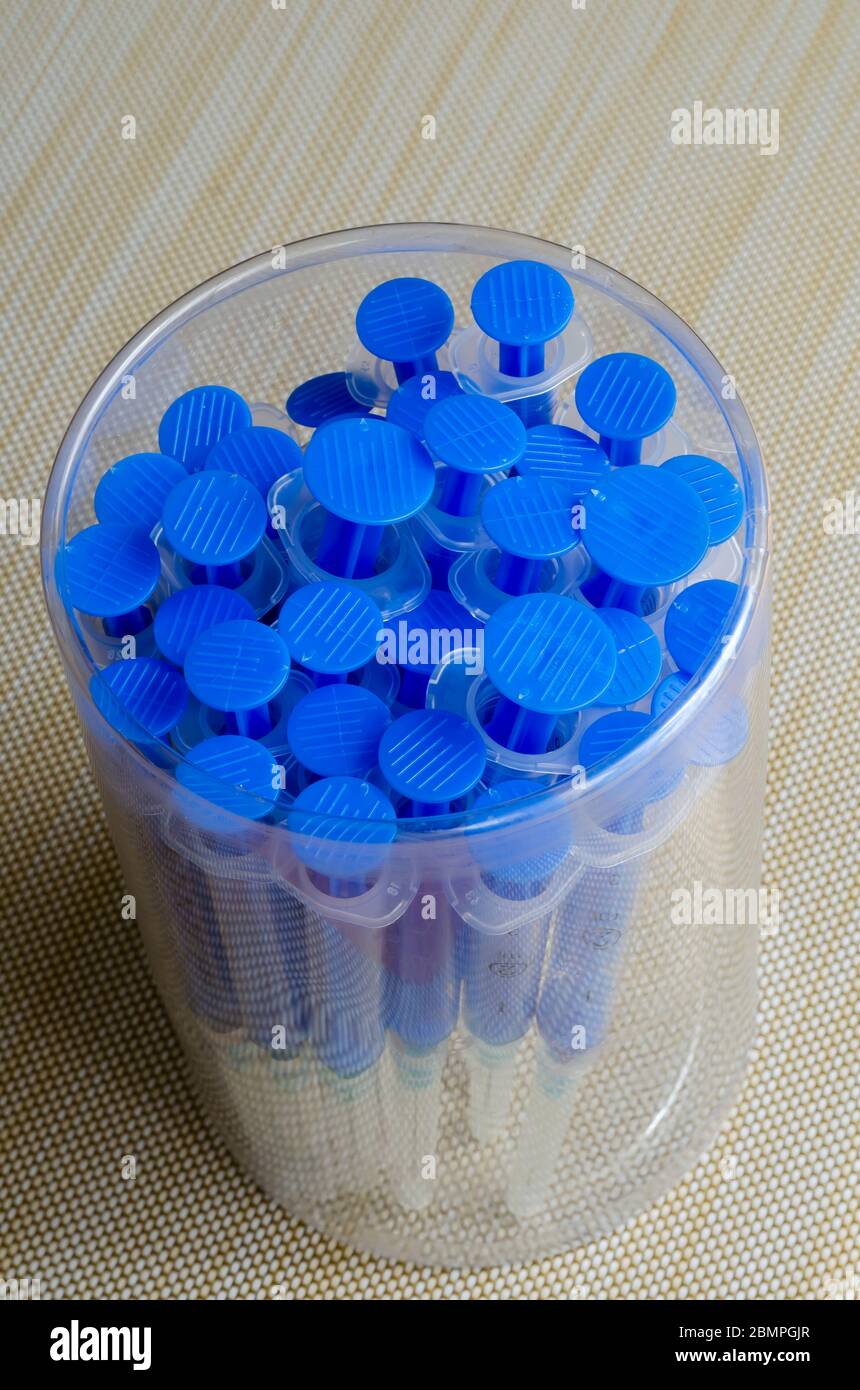 Many used syringes in a plastic jar. Blue medical syringes in a round ...