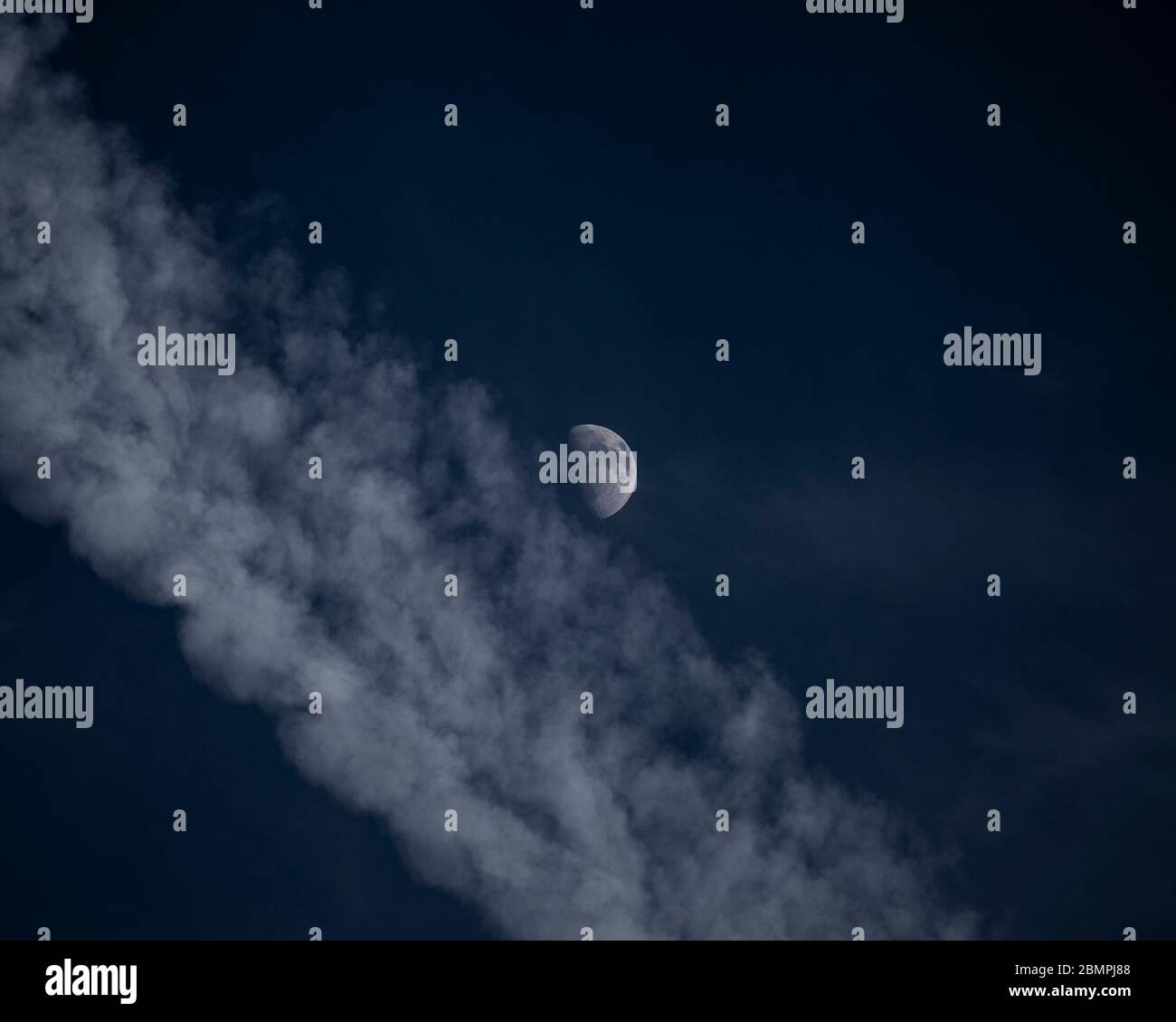 Twilight image of the moon appearing from behind a contrail Stock Photo ...