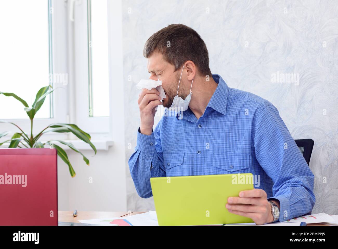 A sick employee sneezes in an office and works remotely Stock Photo - Alamy