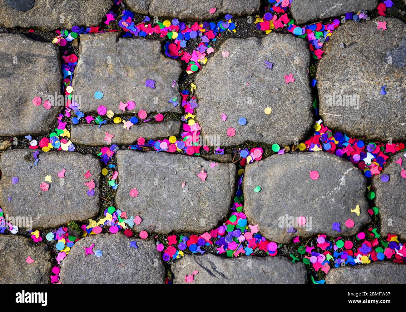 Confetti after a carnival parade between cobblestone pavement, carnival ...