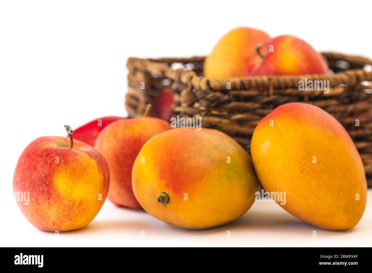 Red apples and mangoes close up. Fresh organic fruits in a wicker ...