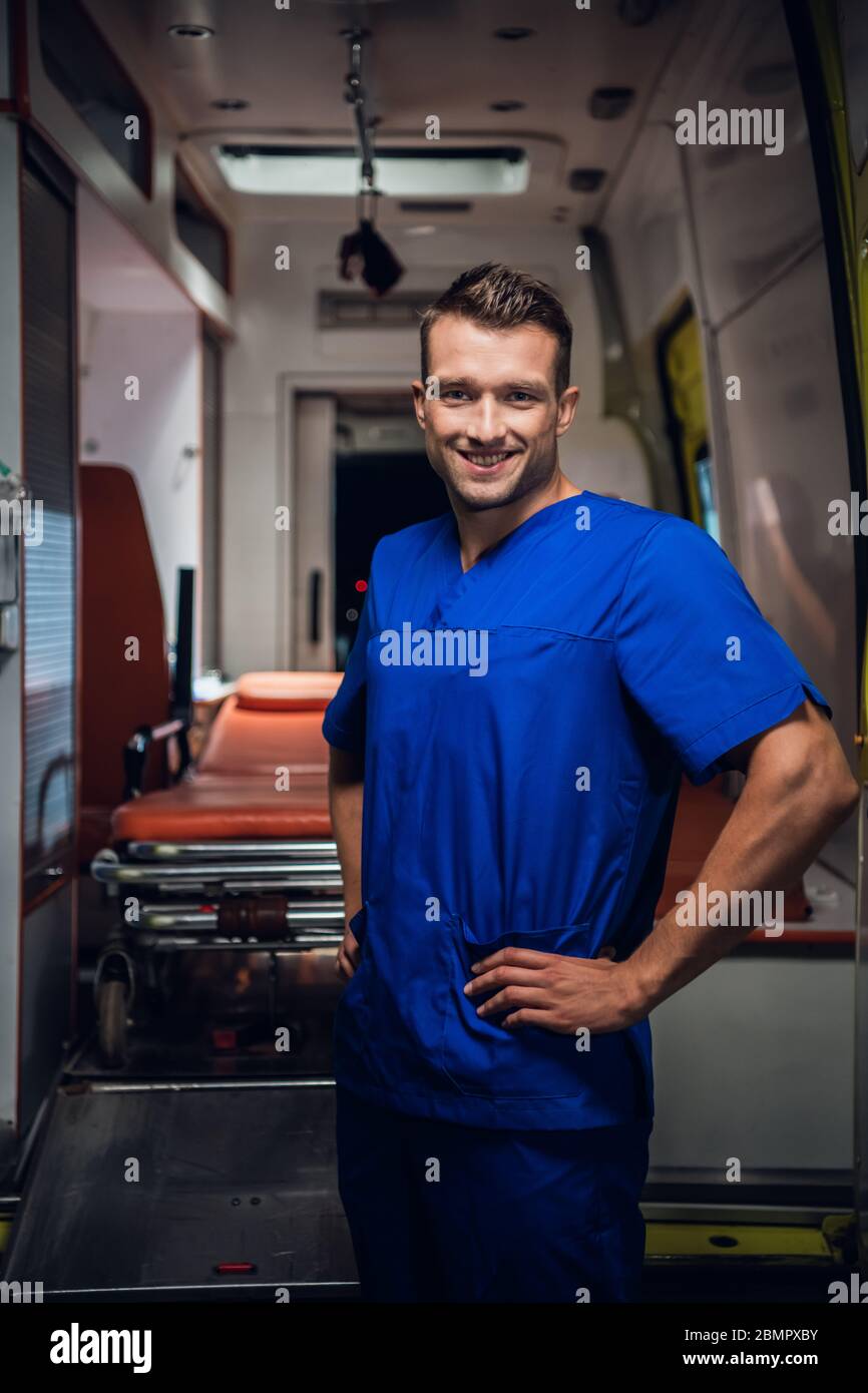 A portrait of a smiling paramedic with an ambulance car in the ...