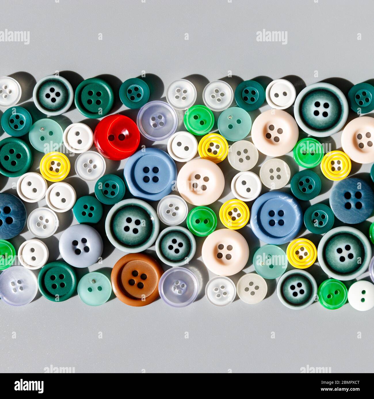 Colorful mixed sewing buttons on grey background, flat lay. Items for ...