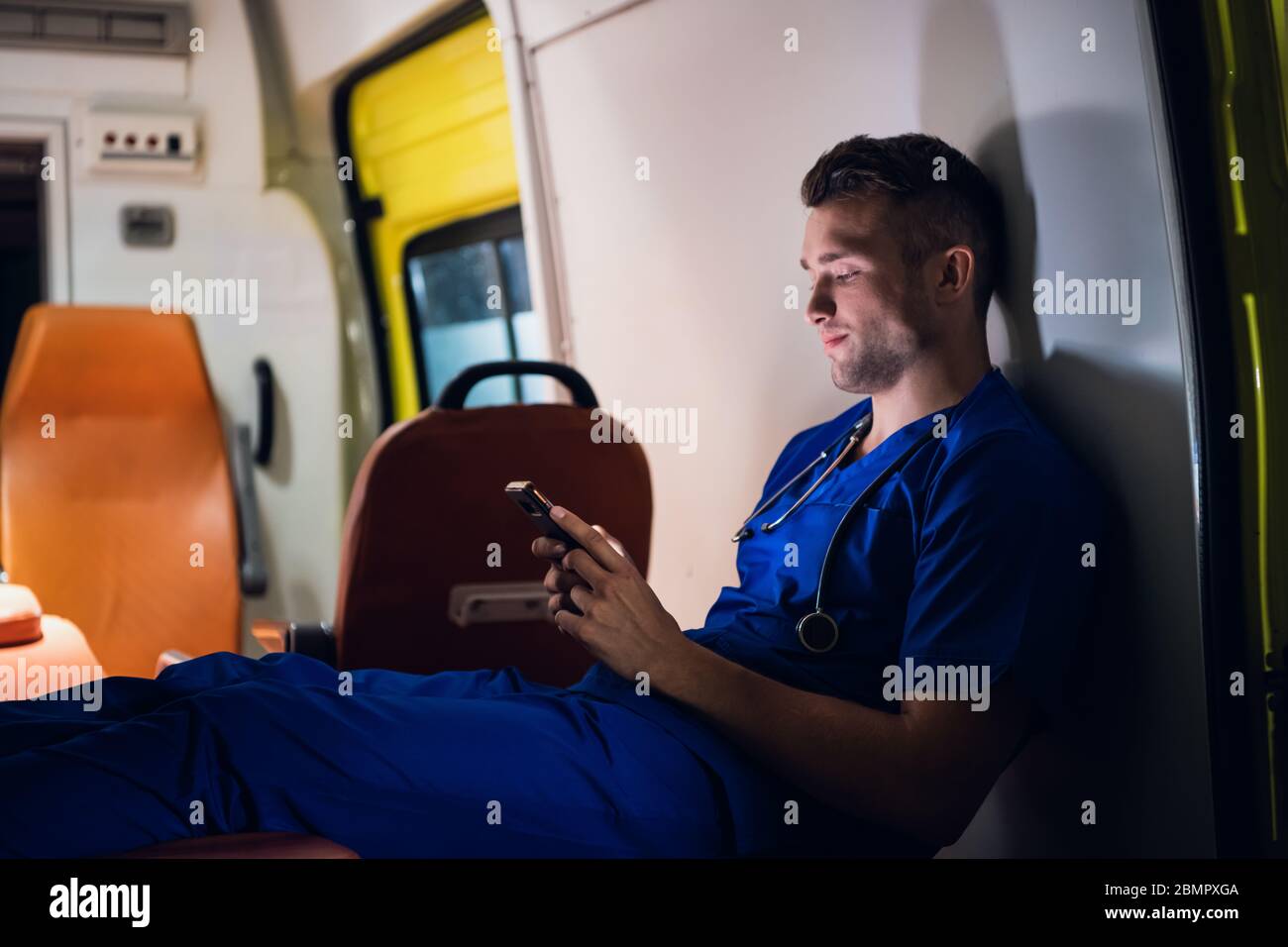 Young paramedic sitting with his smartphone in the ambulance car Stock ...