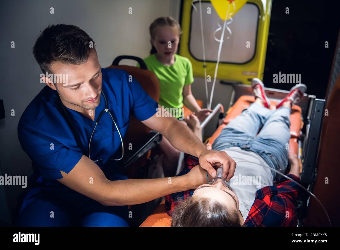 A paramedic puts on an oxygen mask on an unconscious woman lying on a ...