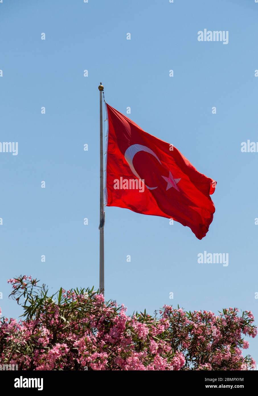 Turkish national flag with white star and moon on a pole in sky beyond ...