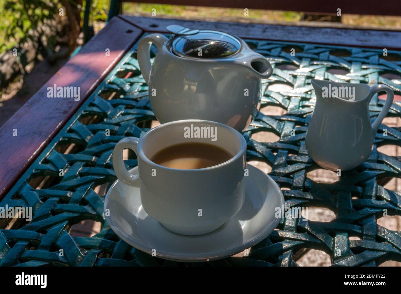 Coffee drink with milk in a white cup on a table outdoors. Coffee, tea ...