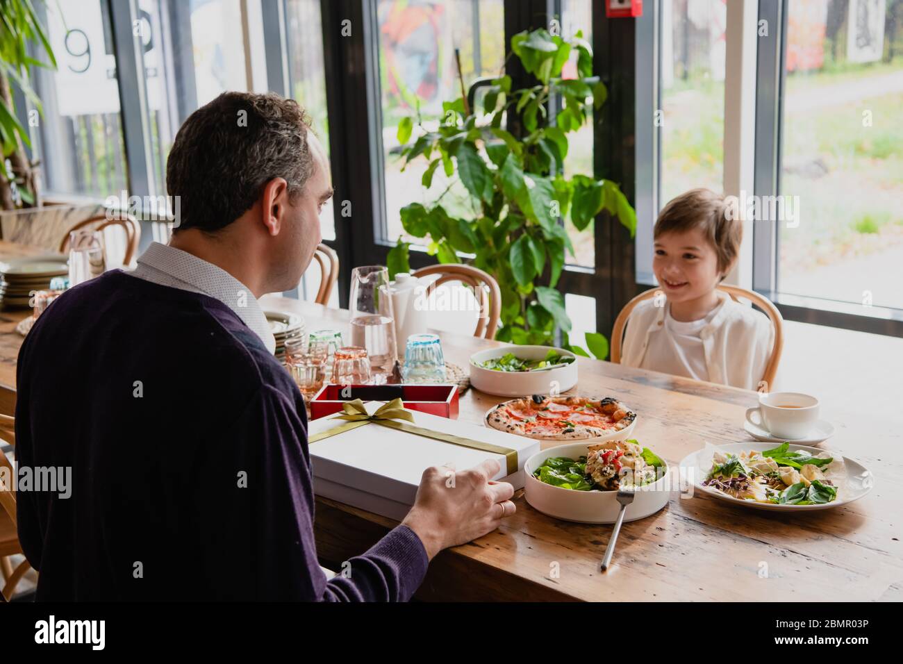 Father and son celebrating in a cafe Stock Photo - Alamy
