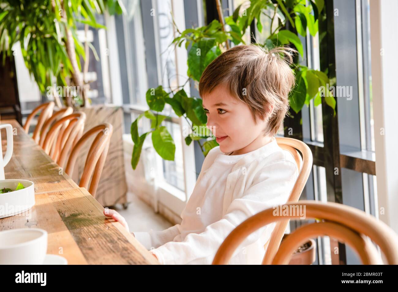 A child sitting at the table and smiling Stock Photo - Alamy