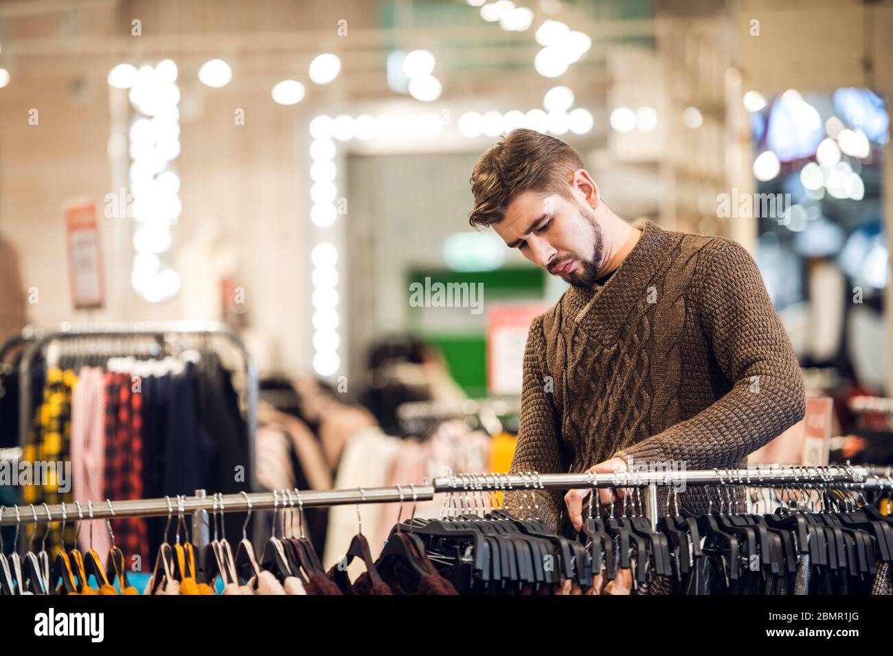 A young man choosing clothing in a retail store Stock Photo - Alamy