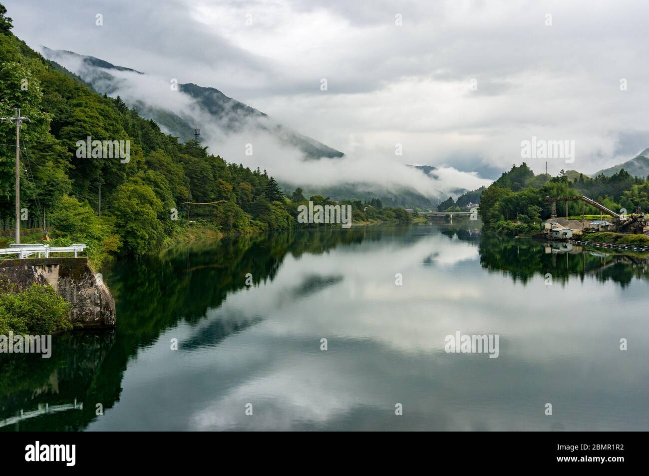 Beautiful river landscape with mountains, green trees and low clouds or ...