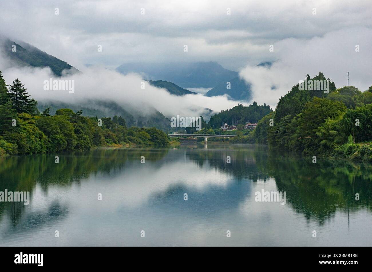 Beautiful river landscape with mountains, green trees and low clouds or ...
