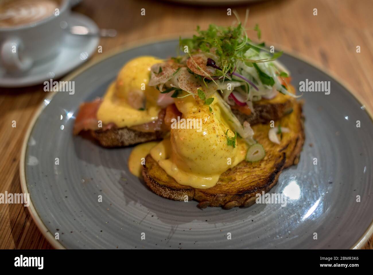 Eggs benedict on sourdough toast with greens and hollandaise sauce ...