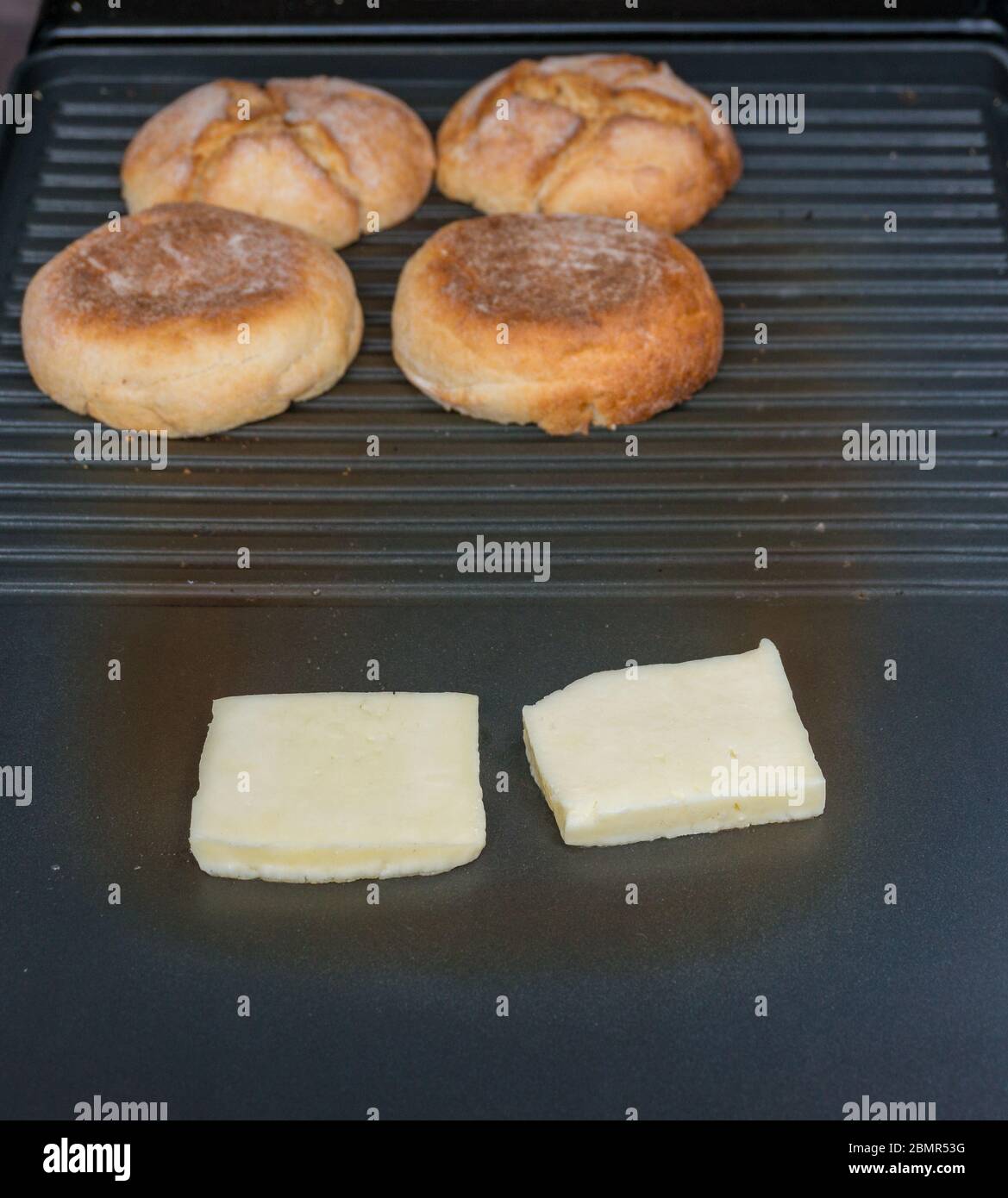 Haloumi cheese squares and halved burger bread bans on grill Stock ...