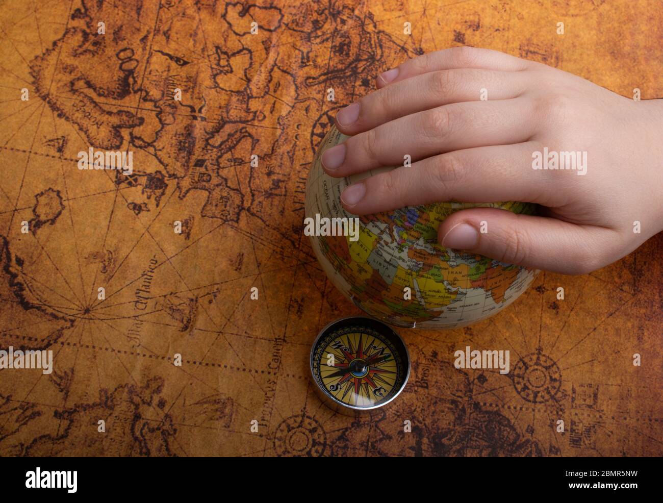Compass on map beside a globe under hand Stock Photo - Alamy
