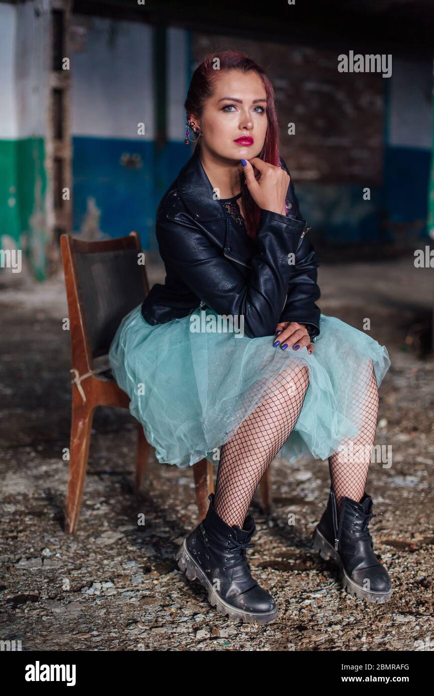 Portrait of a young girl with pink hair sitting old the old chair ...