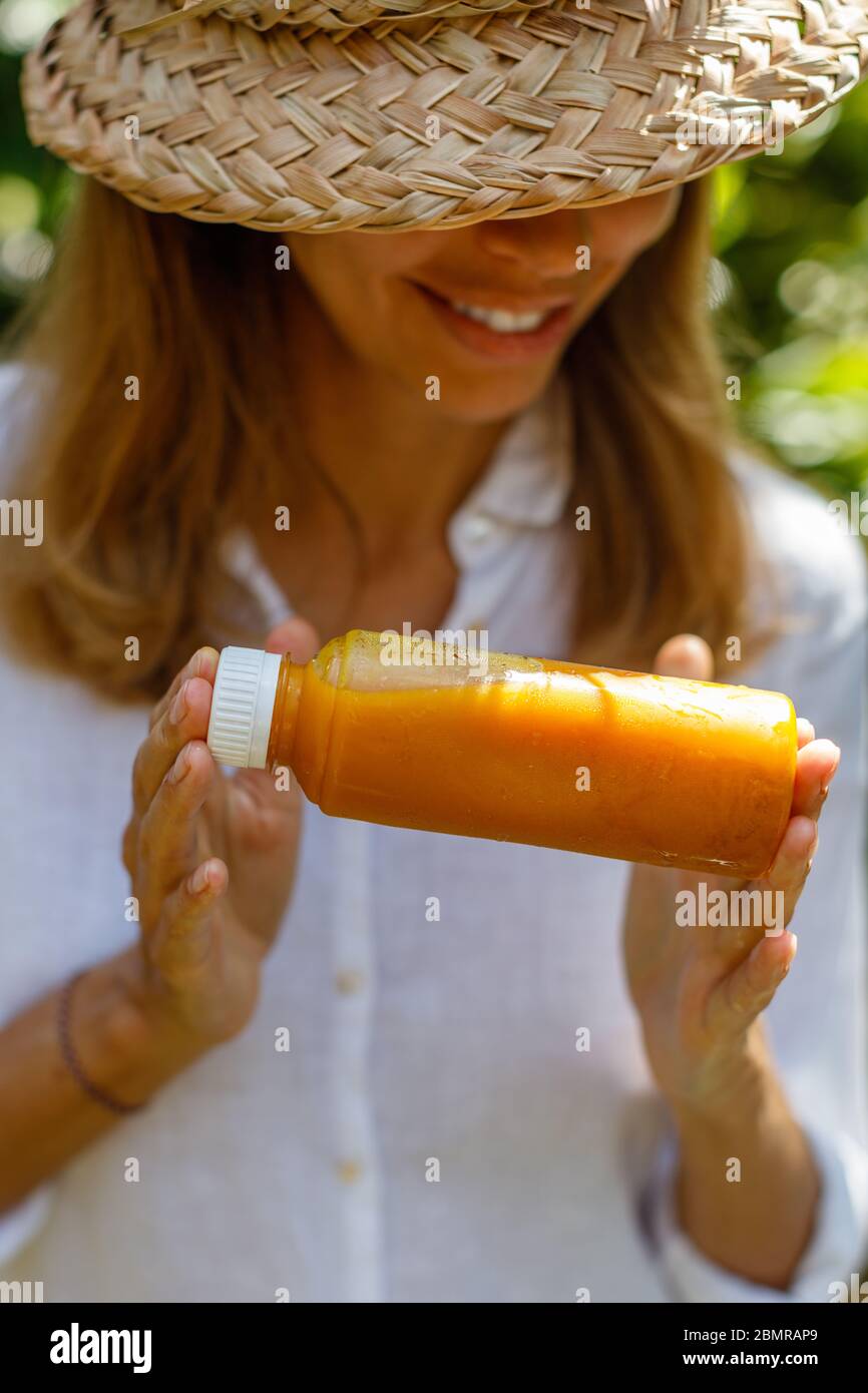 A woman holding a bottle of Jamu "Kunir Asam", traditional Indonesian ...