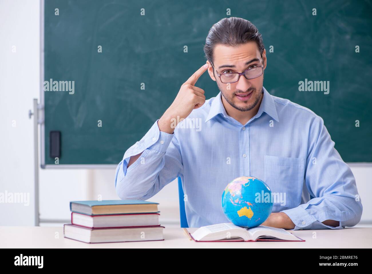 Young geography teacher in front of blackboard Stock Photo - Alamy