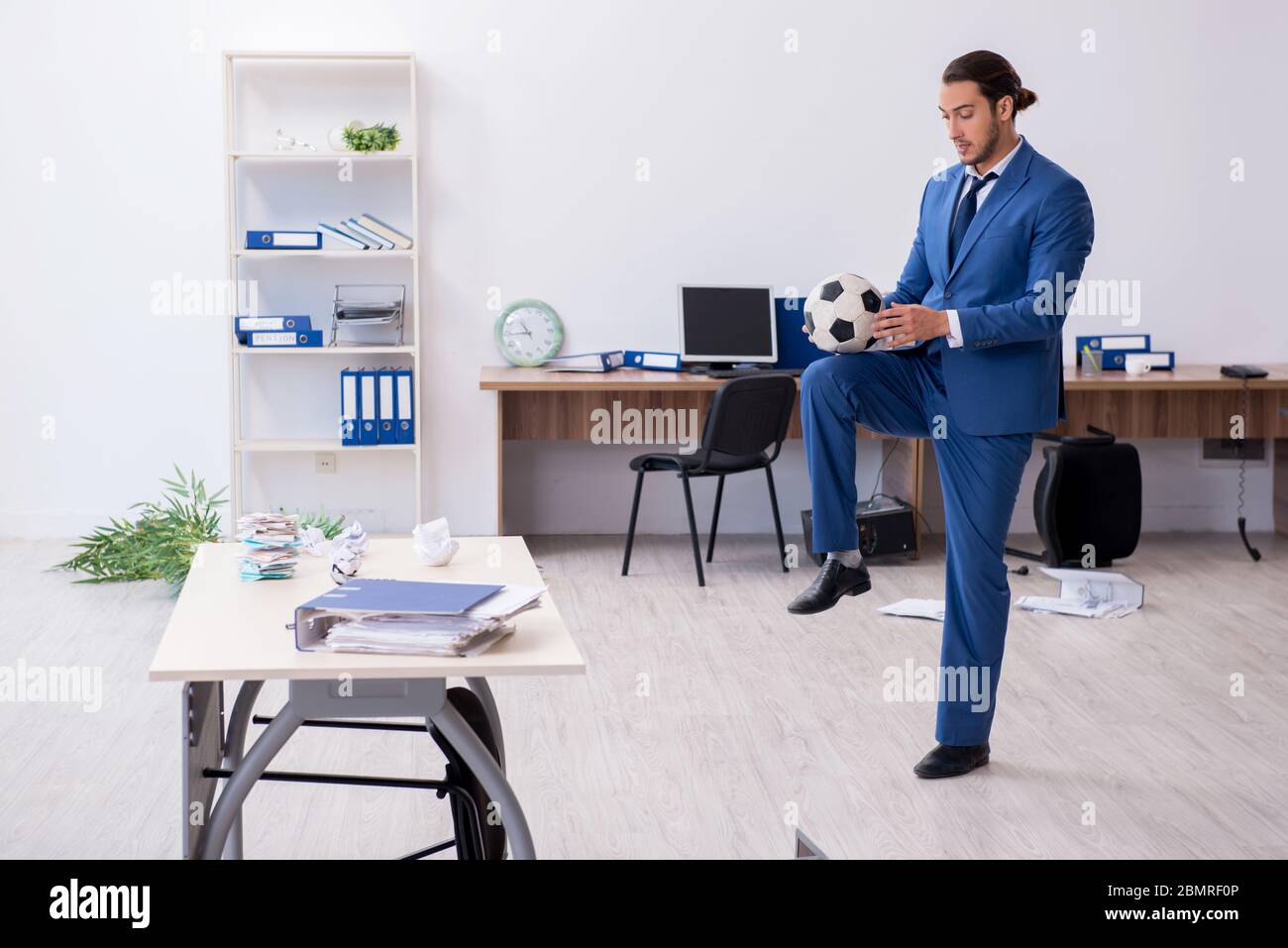 Young employee playing football in the office Stock Photo - Alamy
