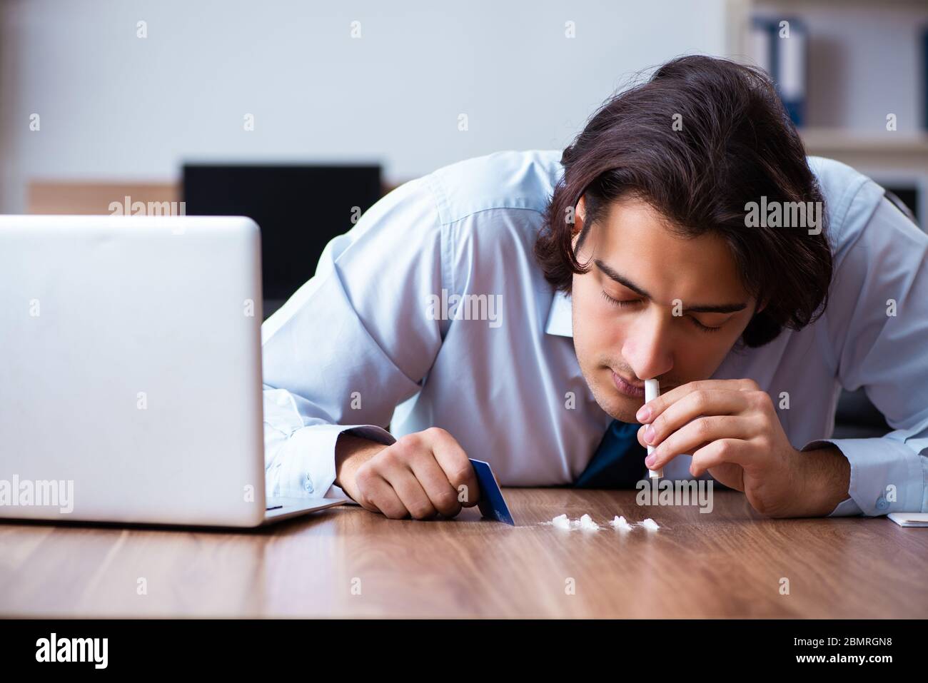The young man having problems with narcotics at workplace Stock Photo ...