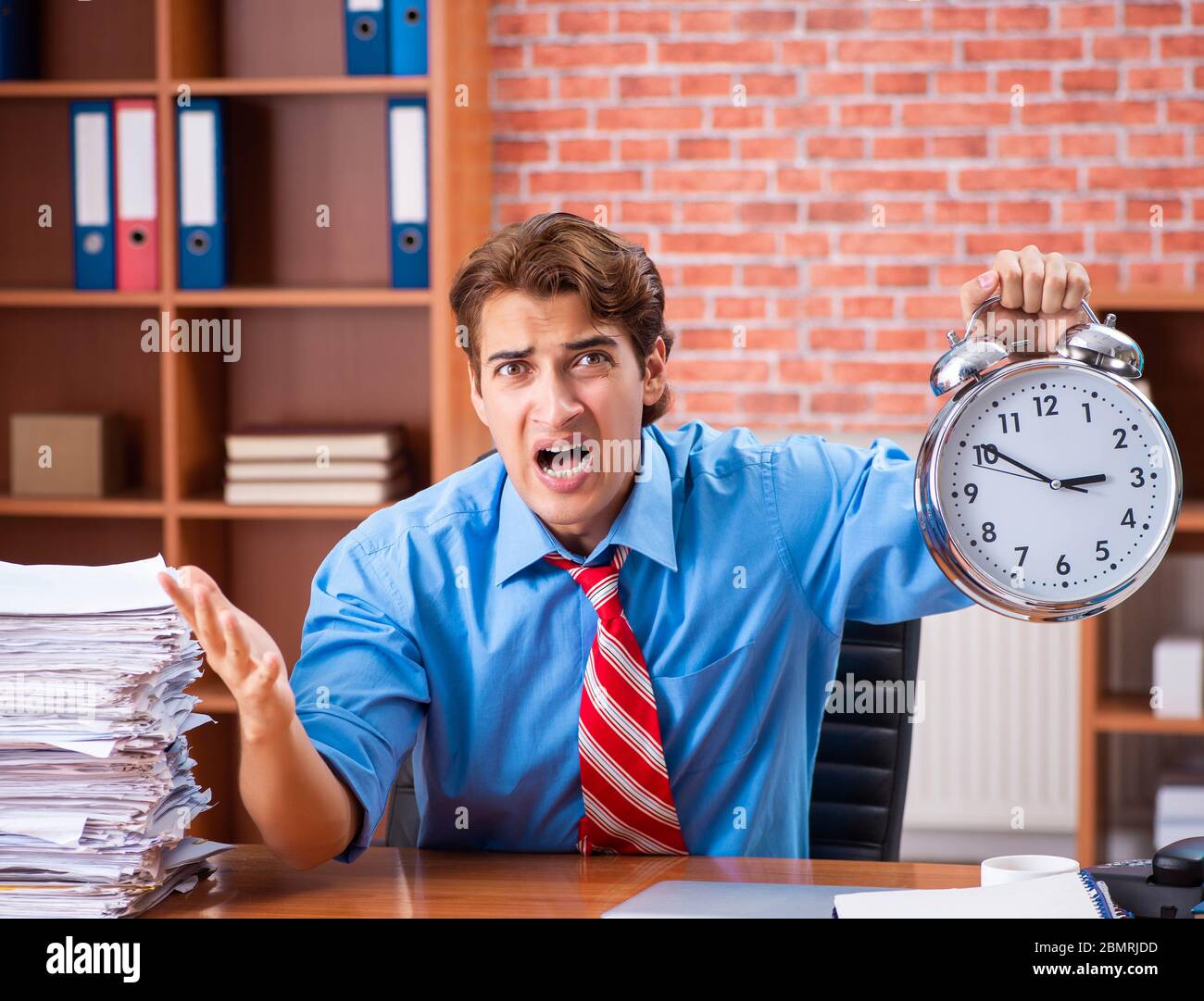 The young employee with excessive work sitting at the office Stock ...