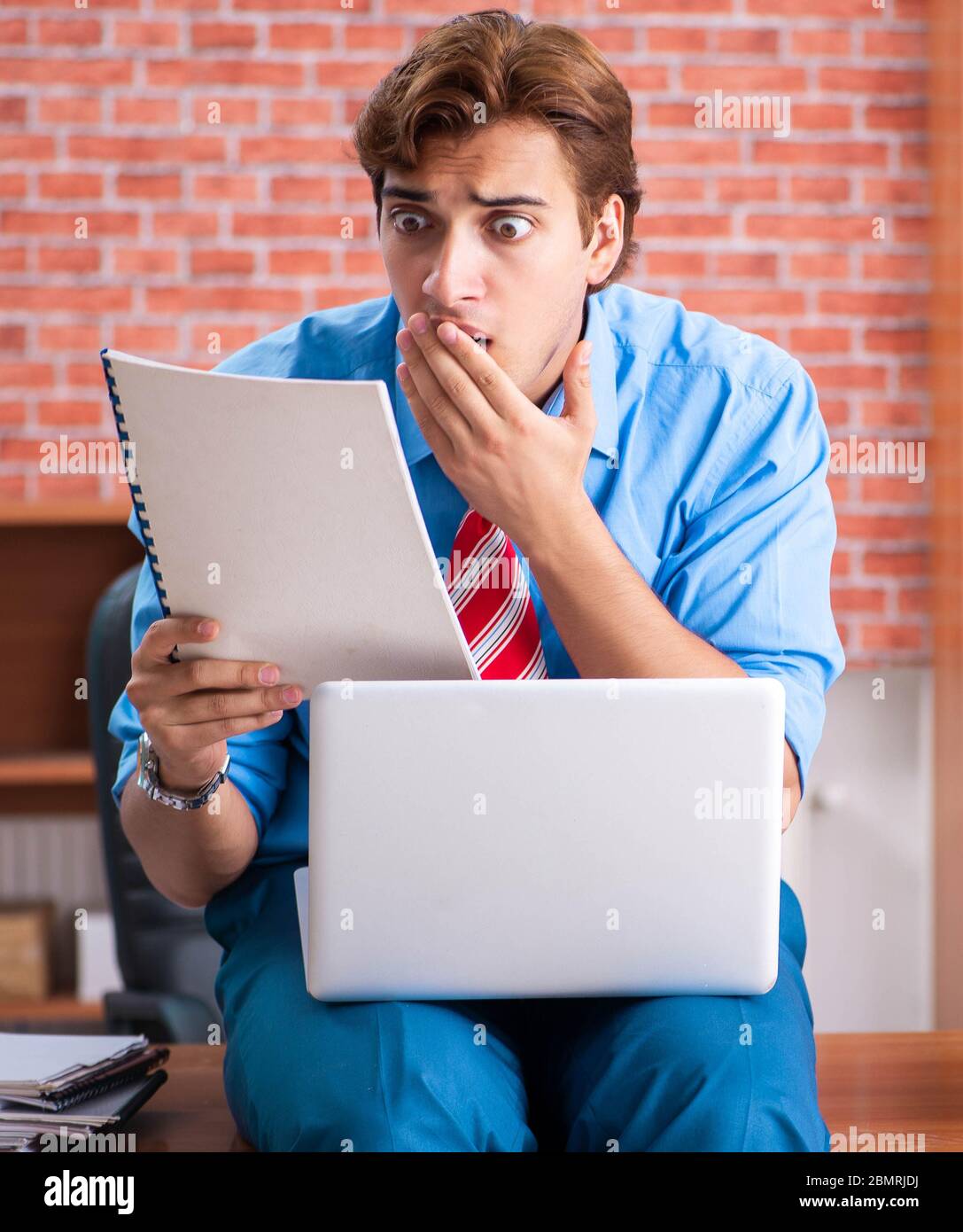 The young employee with excessive work sitting at the office Stock ...