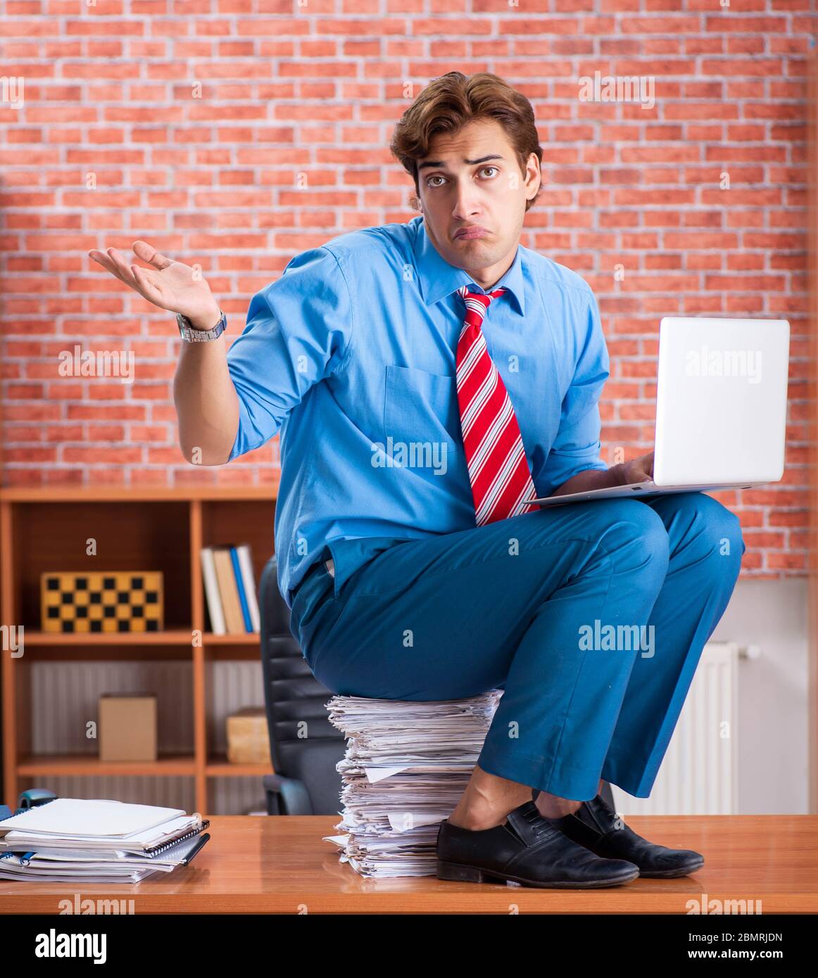 The young employee with excessive work sitting at the office Stock ...