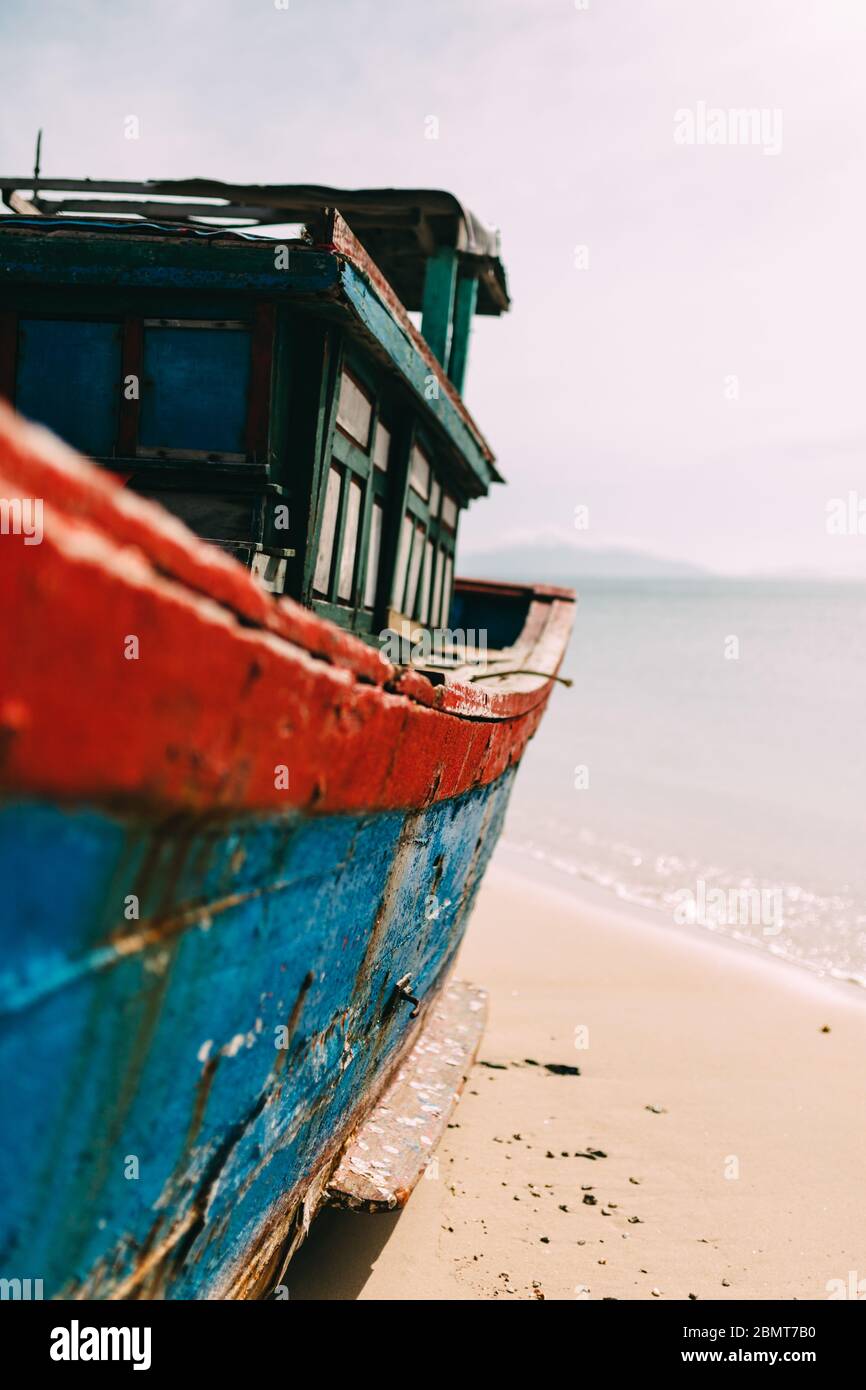 A traditional Asian fishing boat stands in a calm bay on the sandy ...