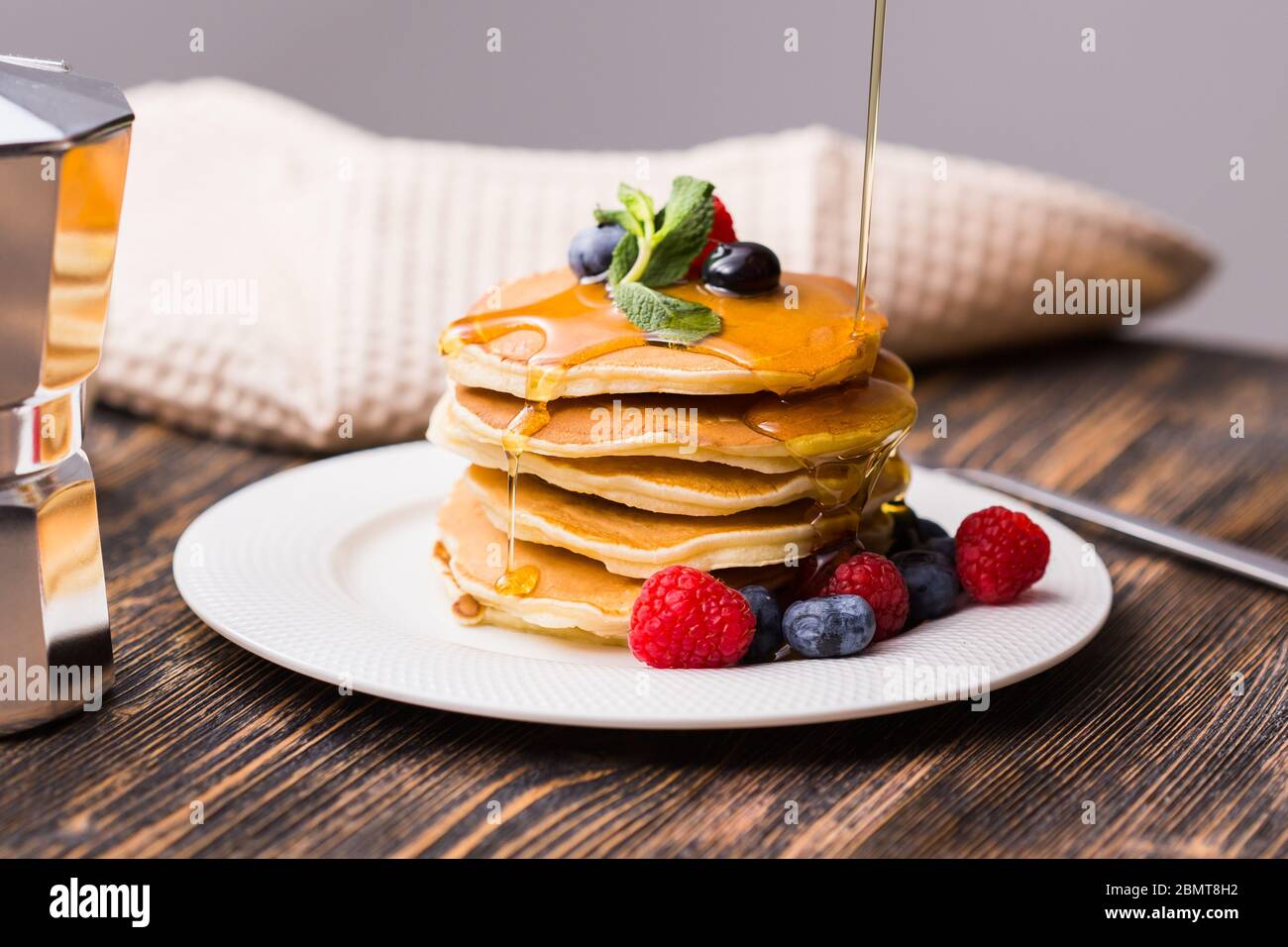 Woman pouring maple syrup on tasty pancakes Stock Photo - Alamy
