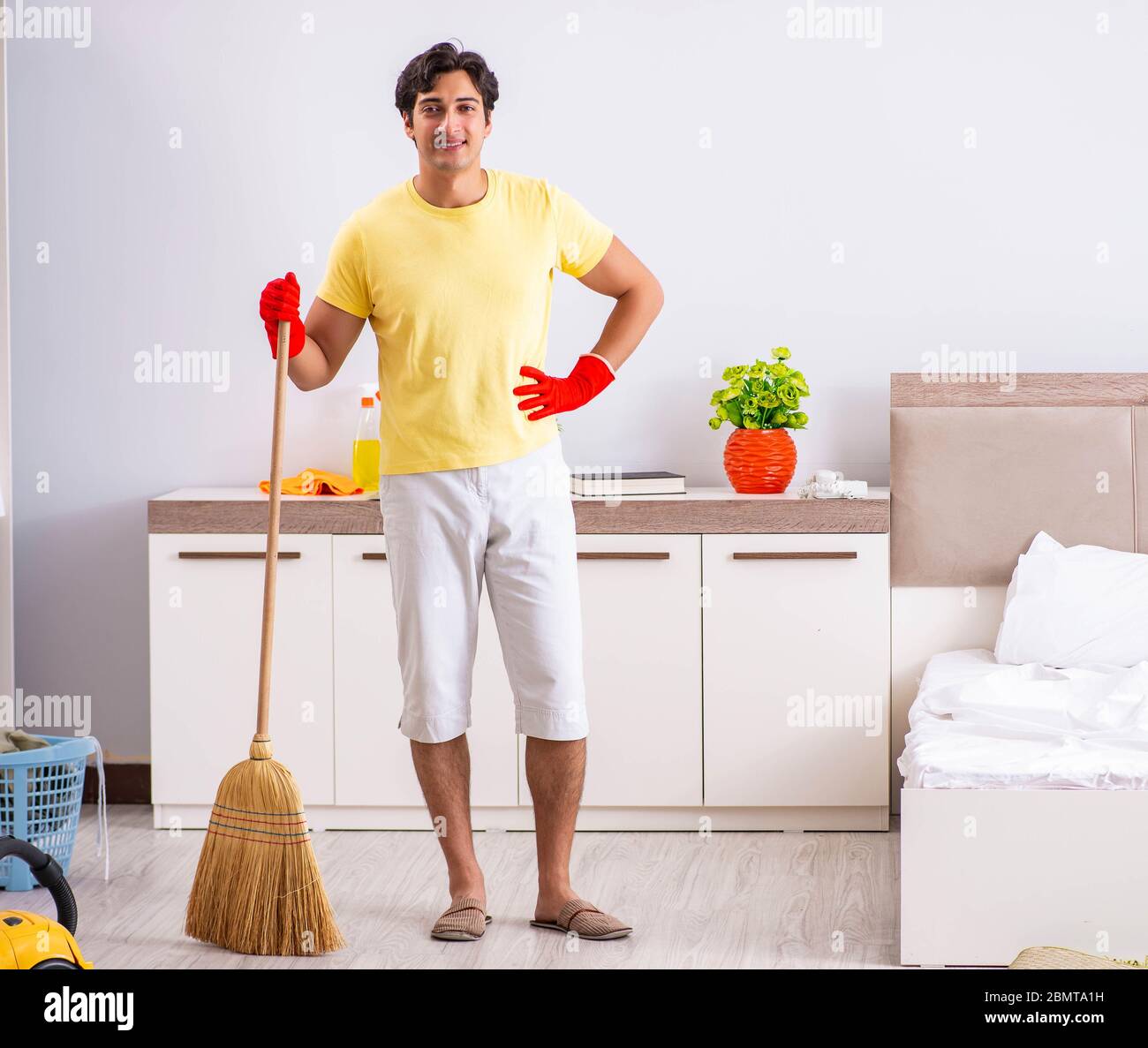 The young handsome man cleaning in the bedroom Stock Photo - Alamy