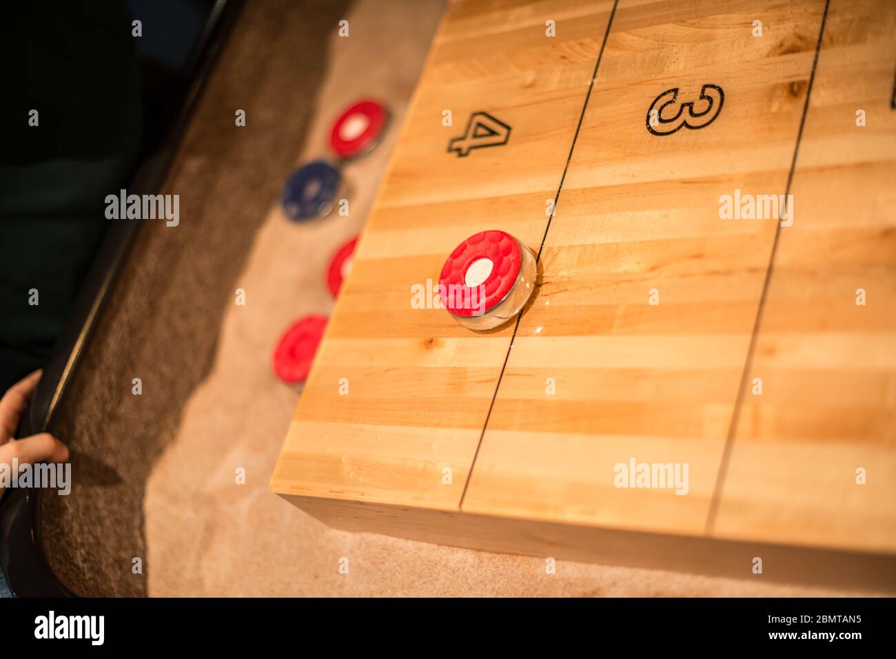 Red puck barely in the 4 point zone of a shuffleboard table Stock Photo ...