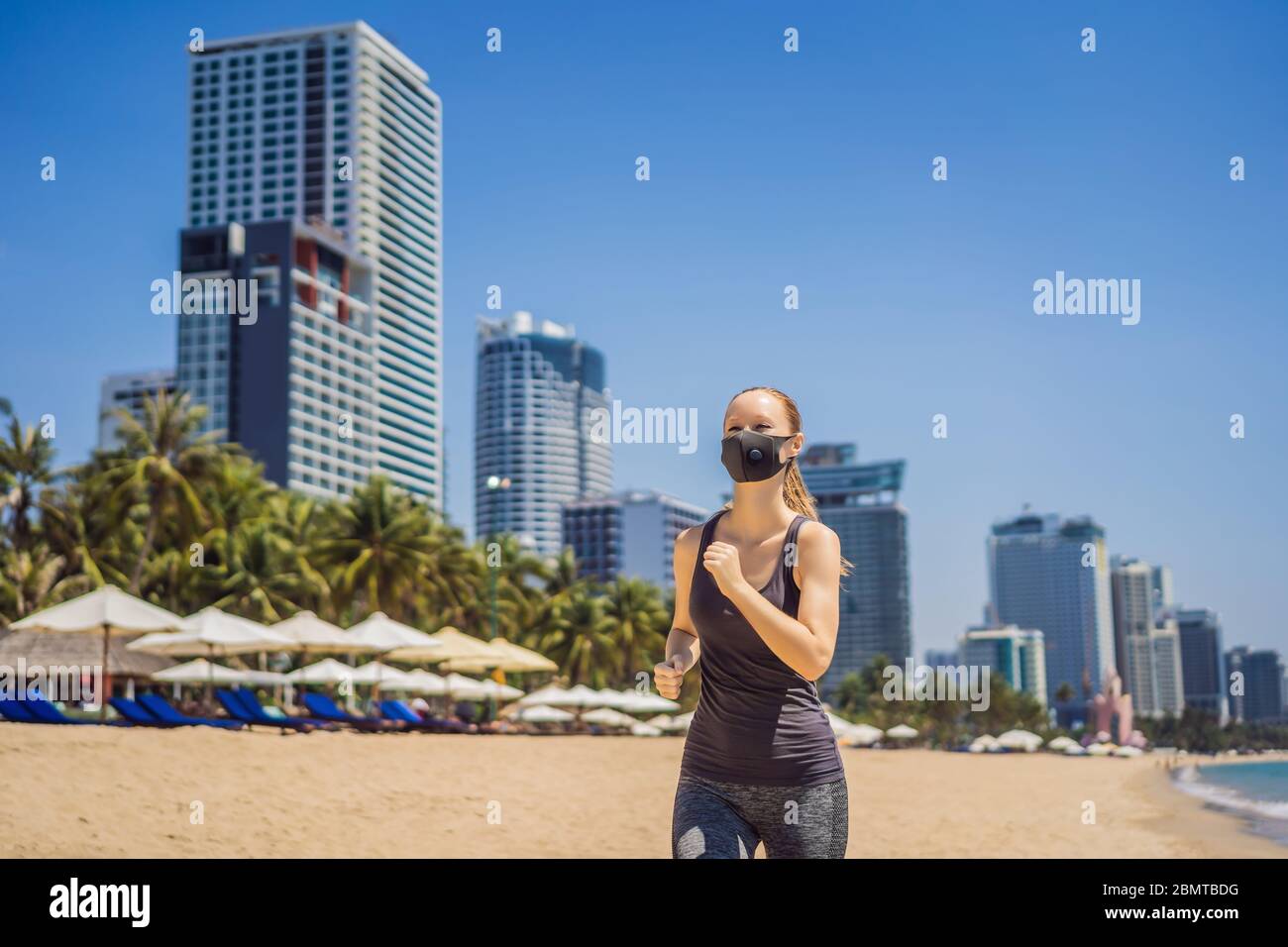 Woman runner wearing medical mask. Running in the city against the ...