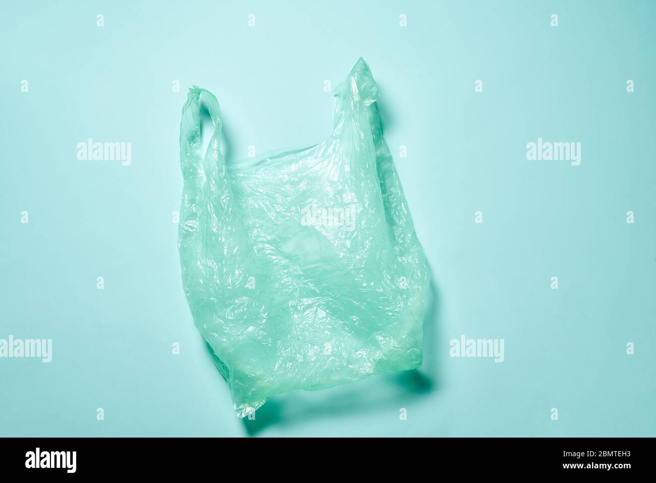Empty plastic green bag over green background Stock Photo - Alamy