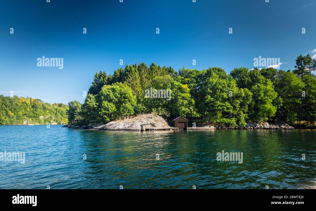 Small brown boat house in a small bay surrounded by trees Stock Photo ...