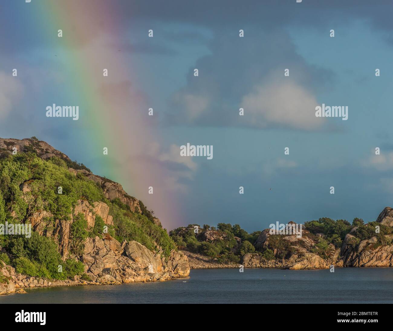 Intense rainbow rising above cliffs Stock Photo - Alamy