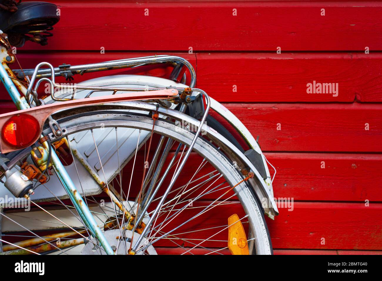 Two old bikes leaning against a red, wooden wall Stock Photo - Alamy